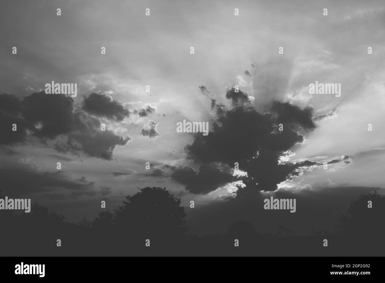 sun rays from a dark cloud during sunset Stock Photo - Alamy