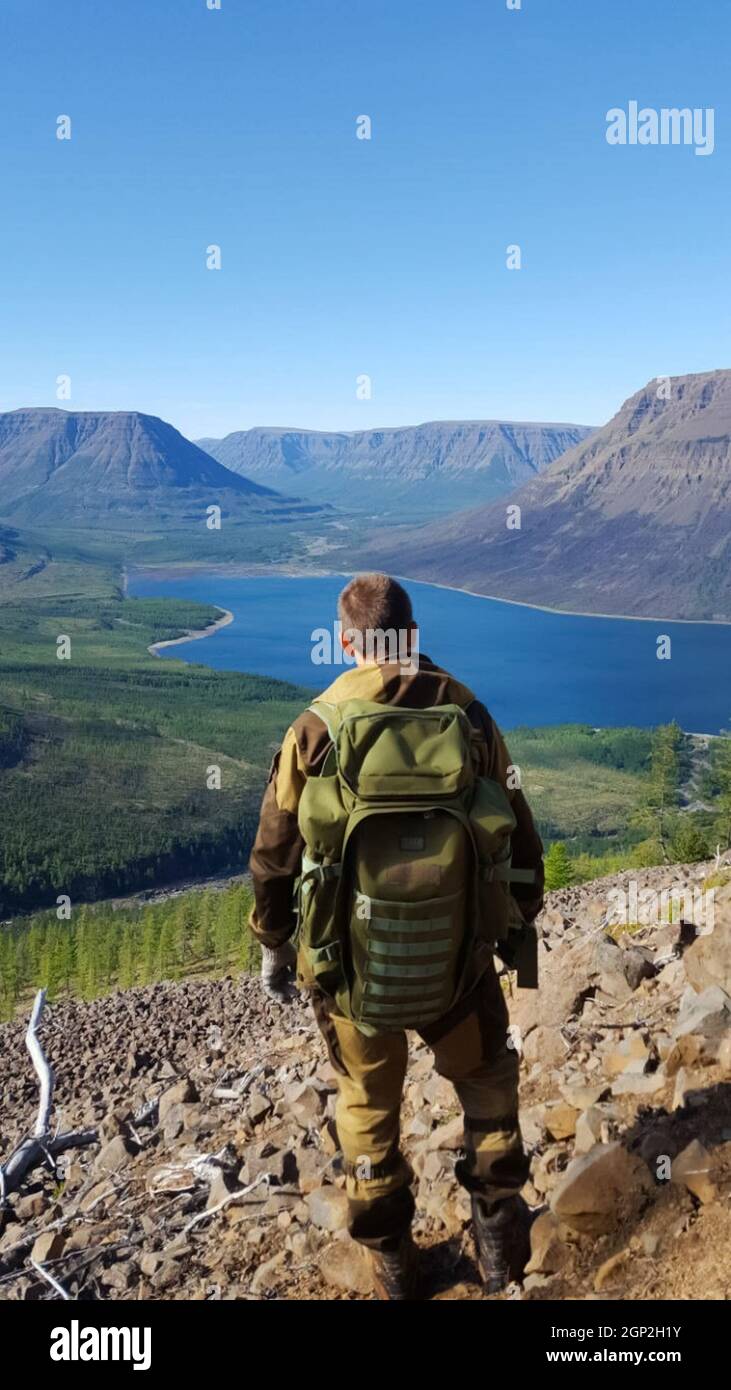 A tourist traveler stands with a backpack over a mountain valley Stock ...