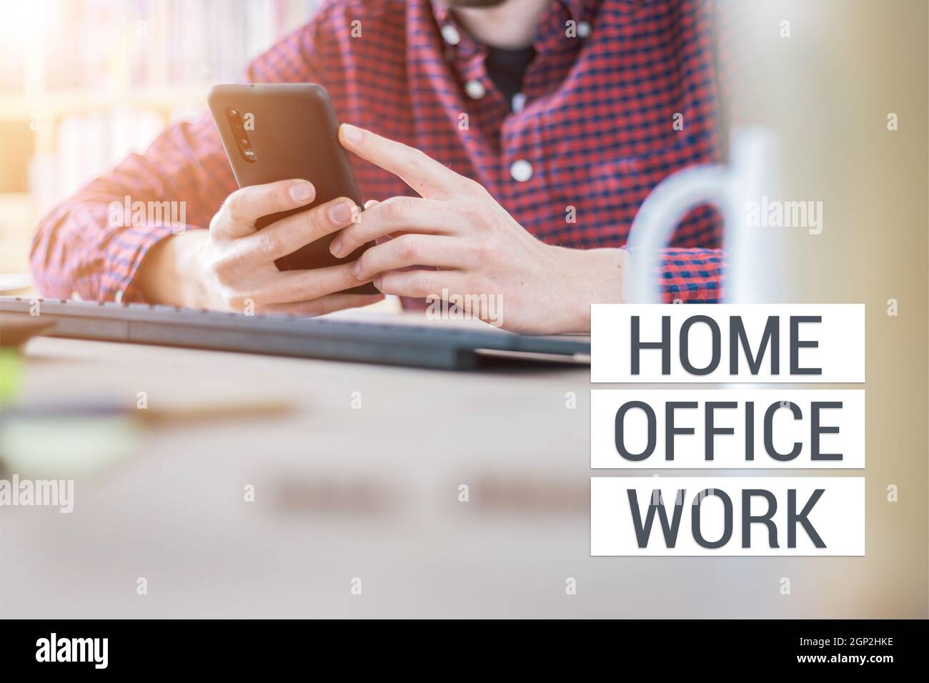 Young man is holding mobile phone in his hands, indoor at home office ...