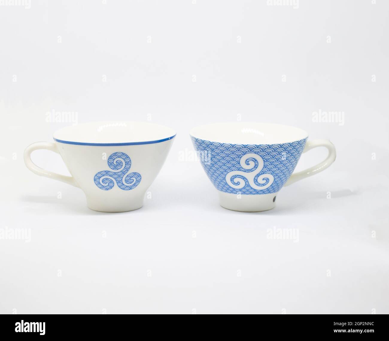 white and blue cup with a blue breton pattern on a white background ...