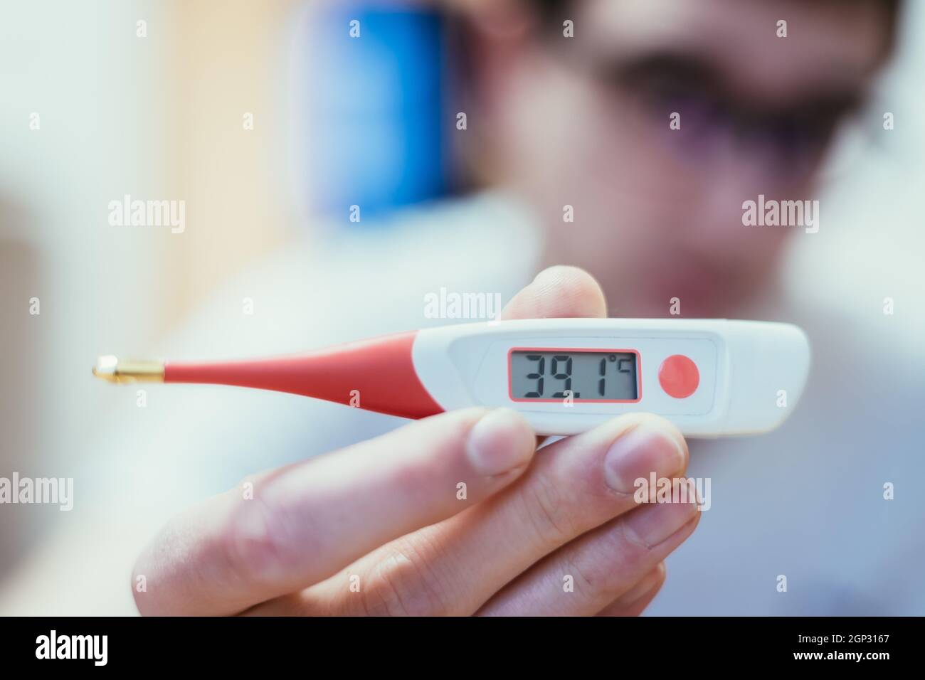 Man is holding a red fever thermometer in his hand Stock Photo - Alamy