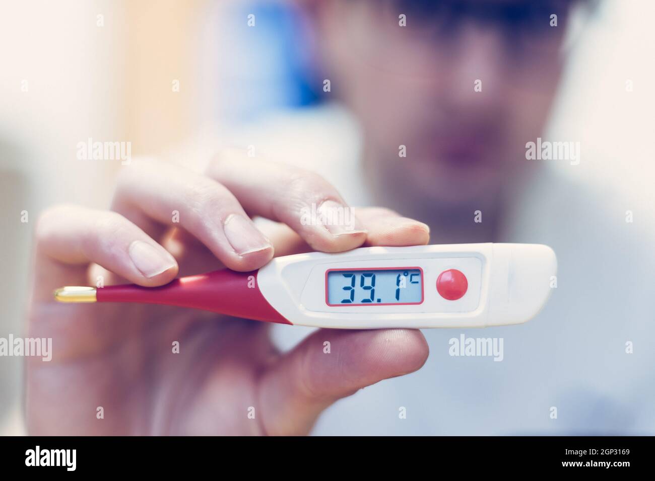 Man is holding a red fever thermometer in his hand Stock Photo - Alamy