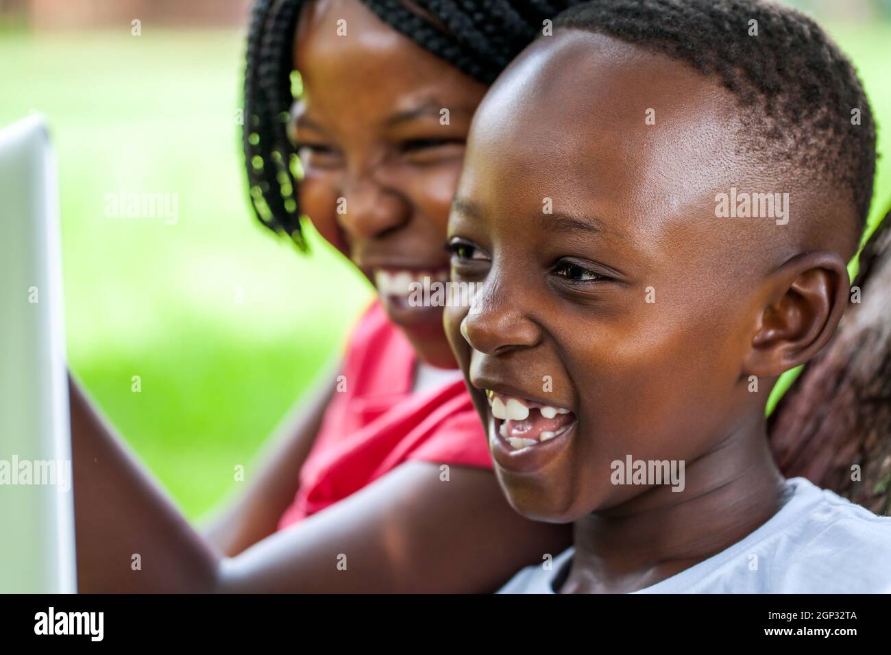 Close up face shot of African kids laughing at movie scene on digital ...