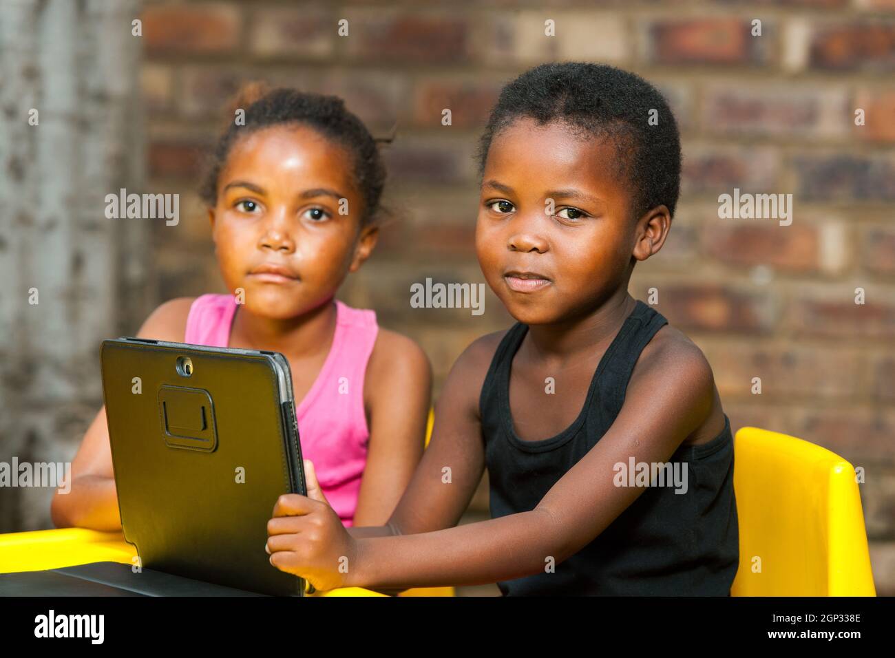 Close up portrait of two african kids with digital tablet outdoors ...