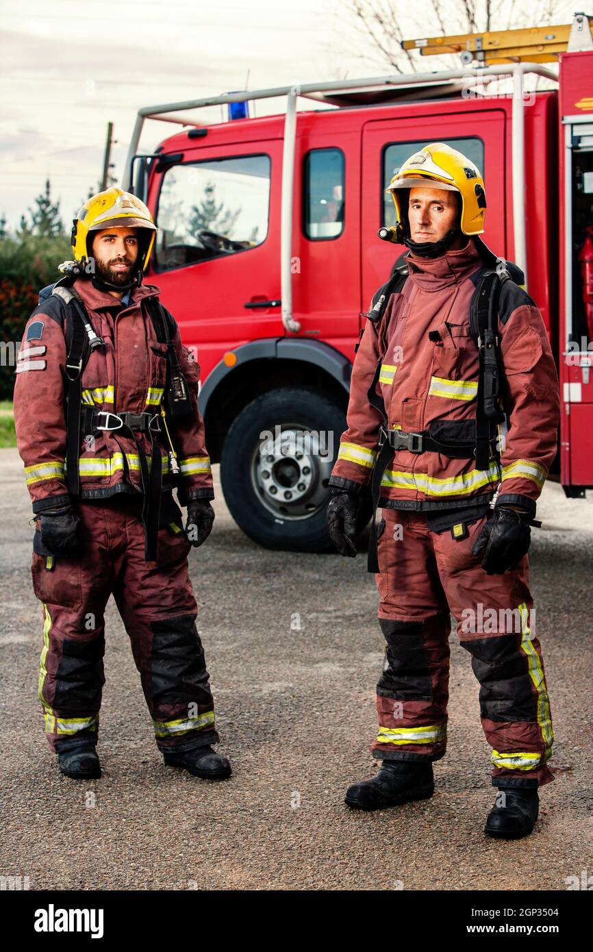Portrait of two firemen standing next to fire truck at base Stock Photo ...