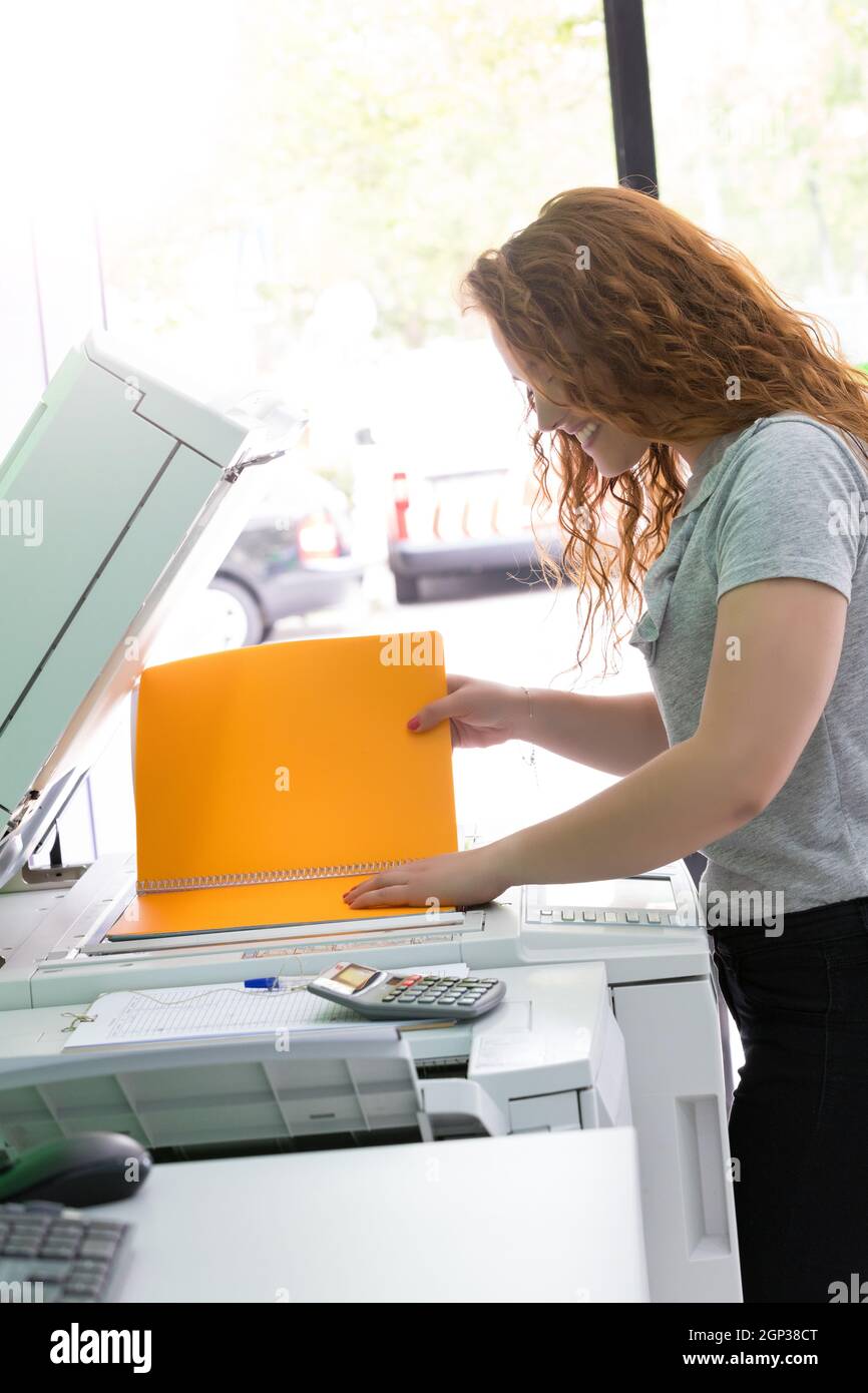 A young student at a copy center taking some copies for her final exams ...
