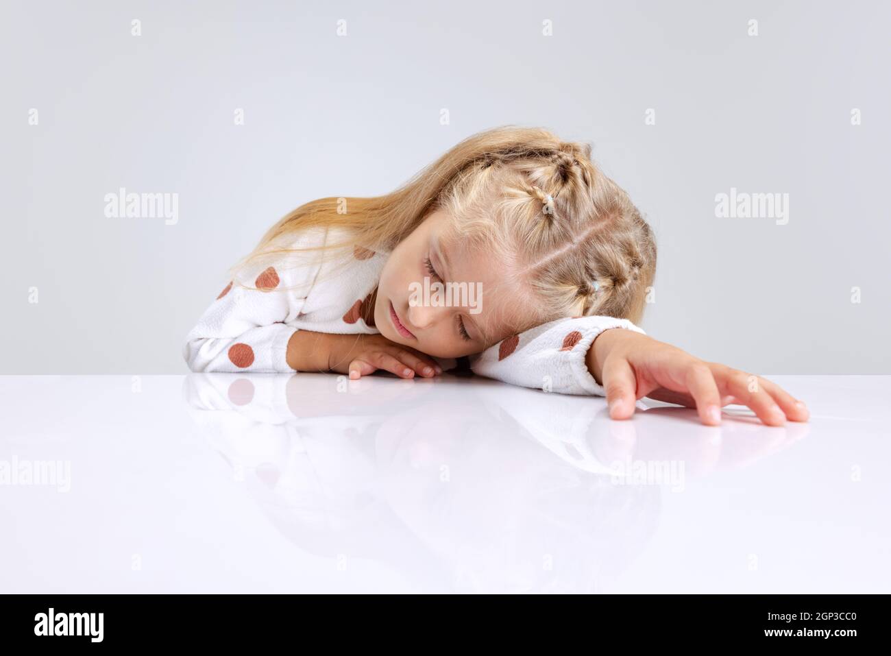 Portrait of little preschool girl lying on the table isolated over ...