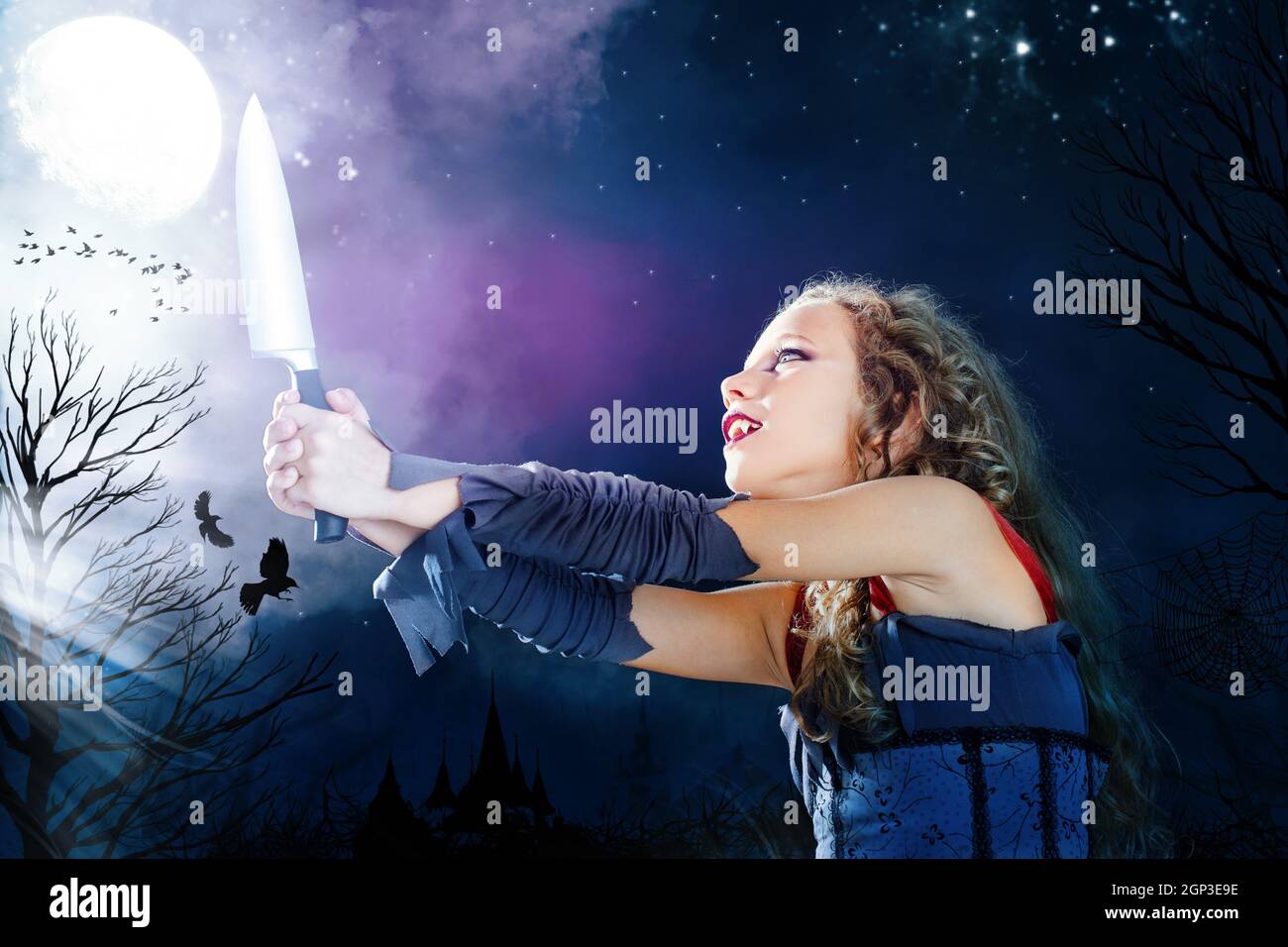Close up portrait of young female vampire holding big knife. Castle ...