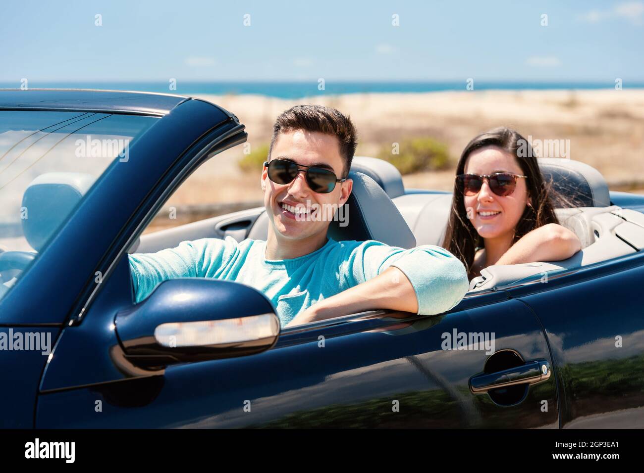 Close up portrait of handsome young man driving convertible along ...