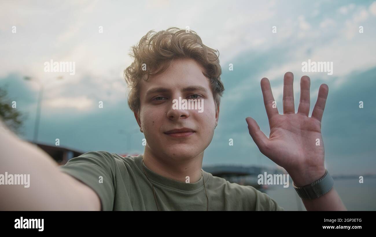 Blond boy record new video or he making video call and waving hand on ...