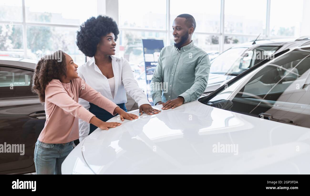 Portrait of happy black family buying new car, making choice in auto ...