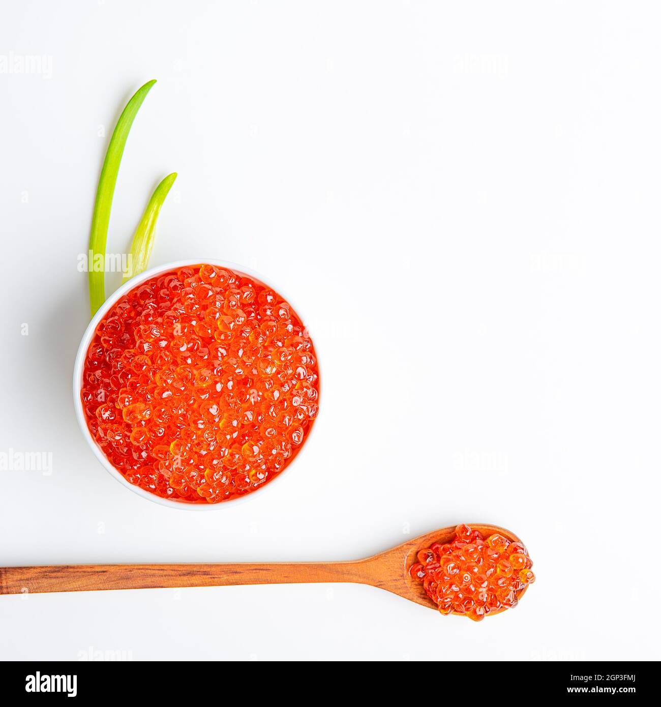 Red caviar in a wooden cup on a white background with a spoon. Place ...