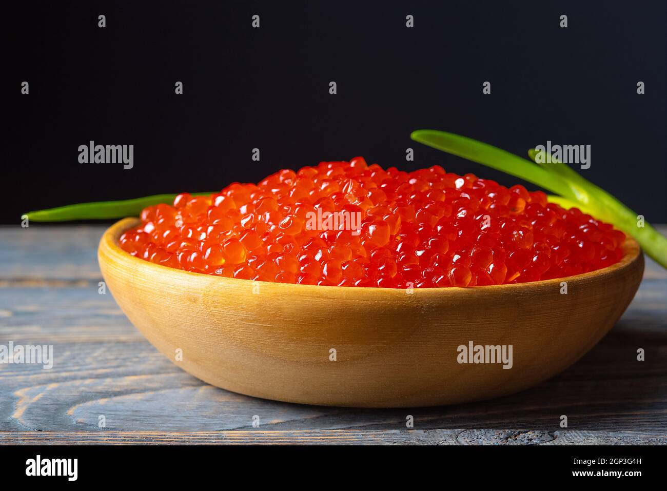 Red caviar in a wooden cup on a wooden background. Place for ...