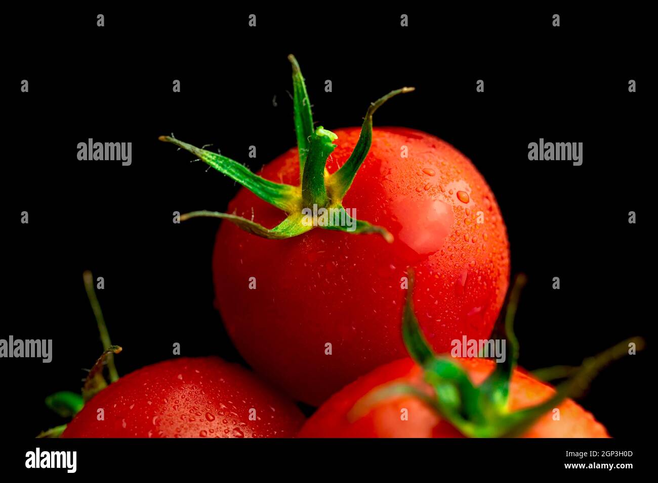 Ripe cherry tomatoes close-up on a black background. Cooking, healthy ...