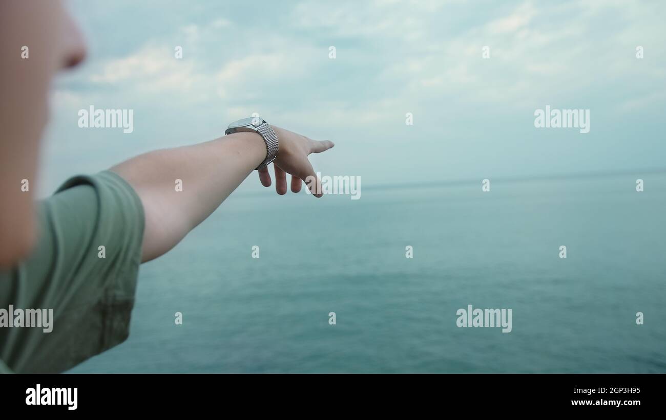 Young man pointing to the horizon with his forefinger while looking out ...