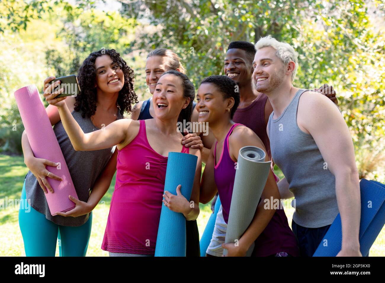 Group of happy fit diverse female and male friends holding yoga mats ...