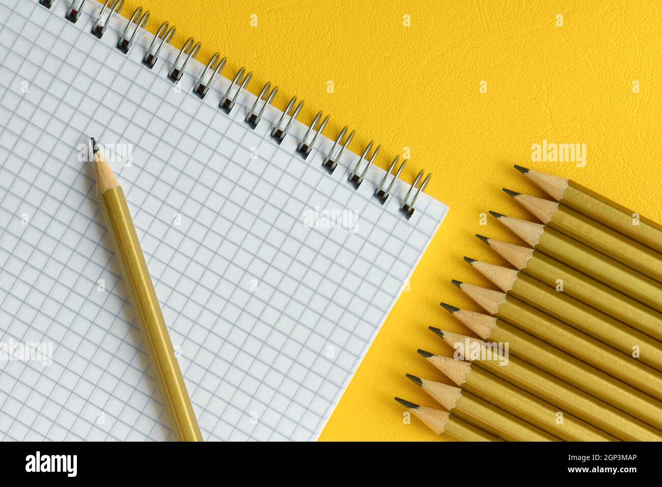 Simple pencils and a notebook in a cage close up, yellow background ...