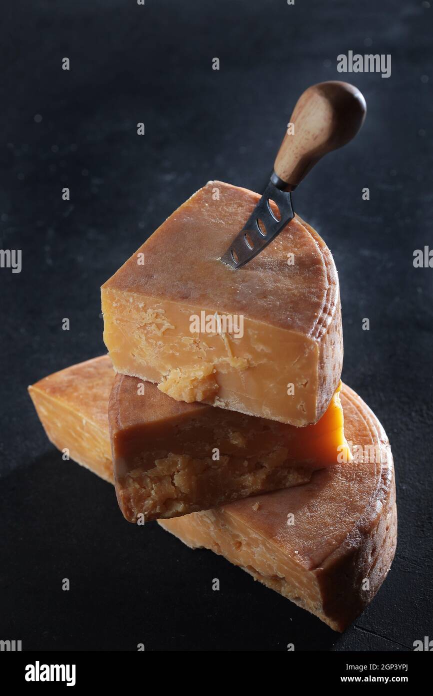 Long-aged cheese chunks. Hard cheese with a knife on a dark background ...