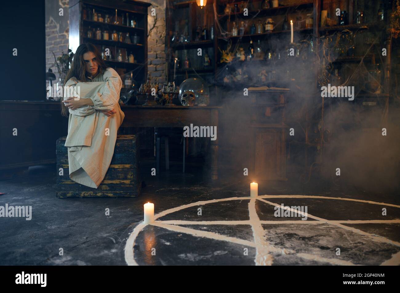 Young demonic woman sitting near magic circle with candles, demons ...
