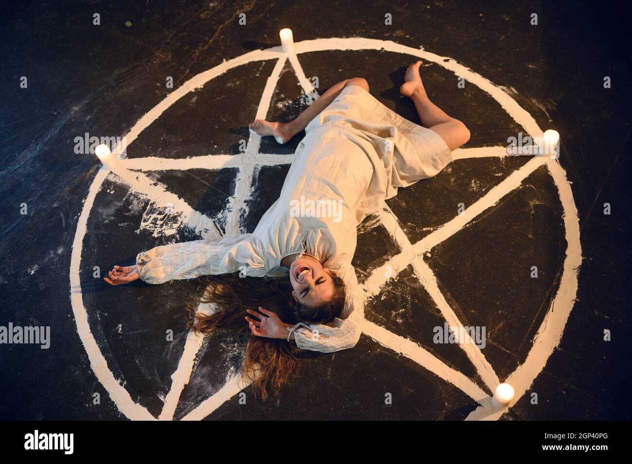 Scary demonic woman lying in magic circle with candles, demons casting ...