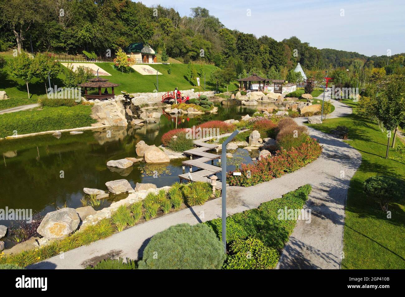 A beautiful landscape park, a lake, wooden pavilions, a red bridge in ...