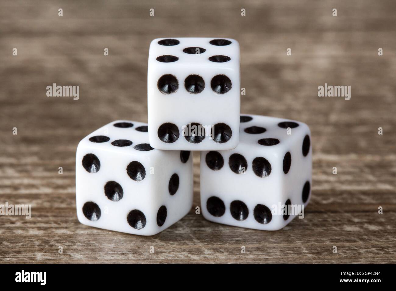 Three dice on dark wooden table background Stock Photo - Alamy