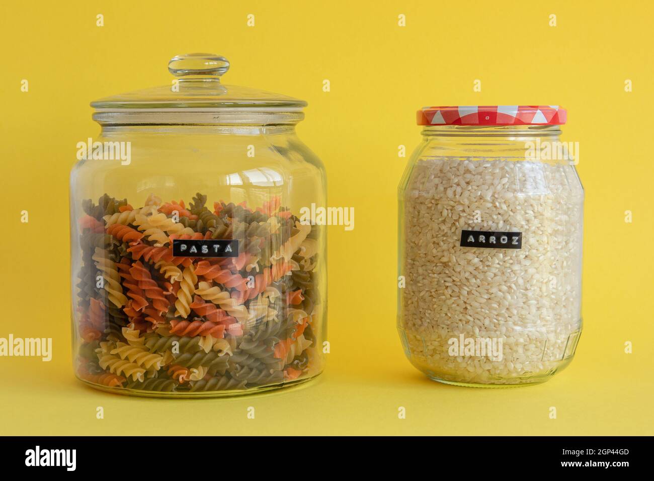 Two glass jars filled with colorful spiral pasta and rice isolated on ...