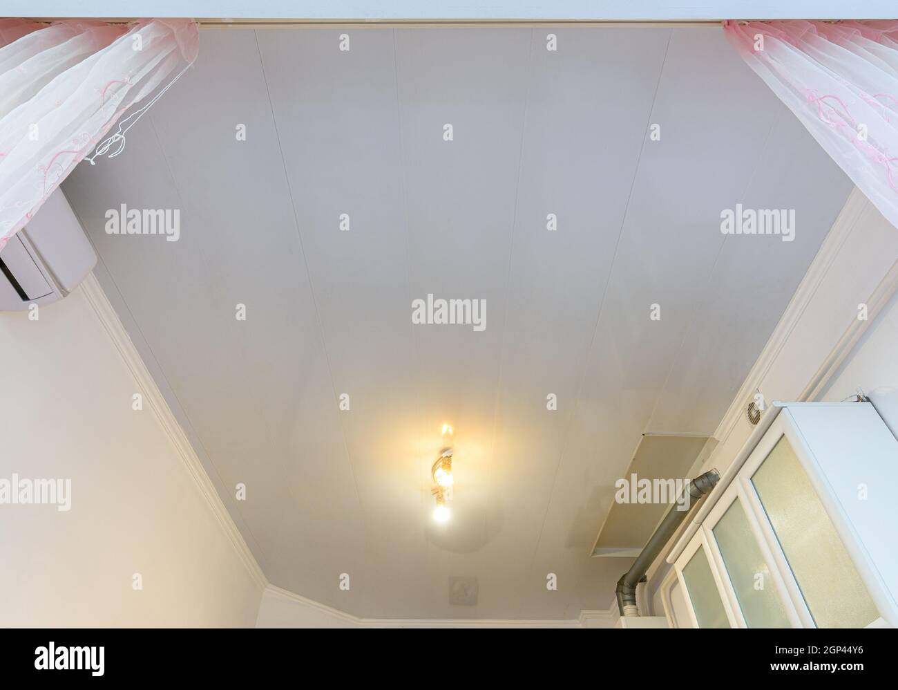 A budget ceiling made of white plastic panels in a spacious kitchen ...