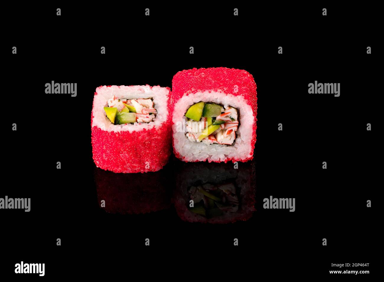 Two red tuna rolls with red caviar and shrimp on a black background ...