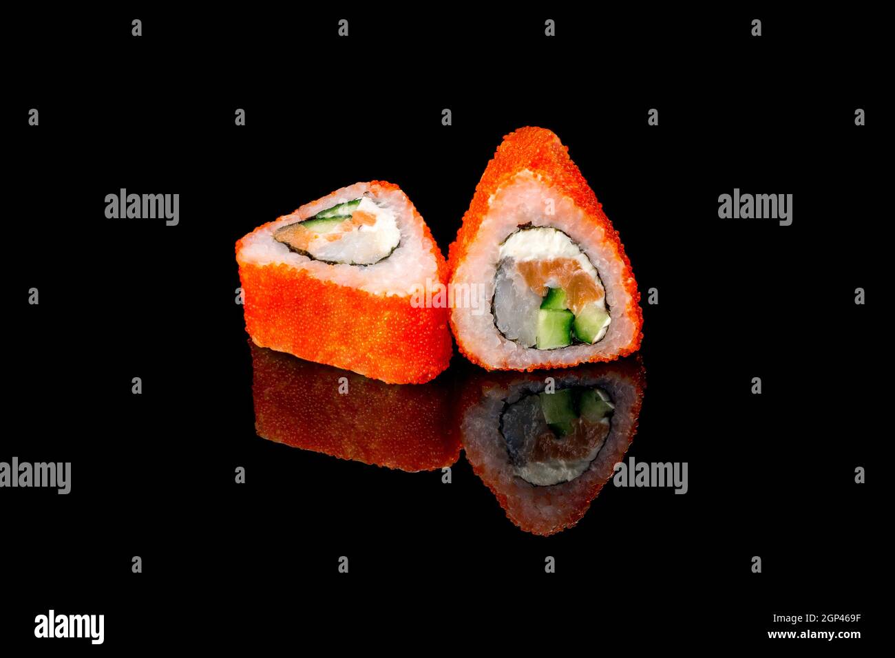 Two red tuna rolls with red caviar and shrimp on a black background ...
