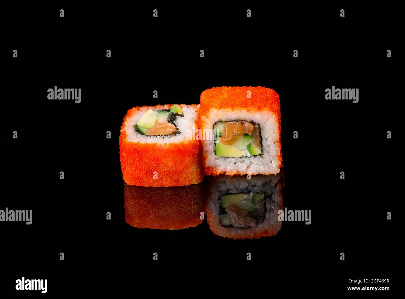 Two red tuna rolls with red caviar and shrimp on a black background ...