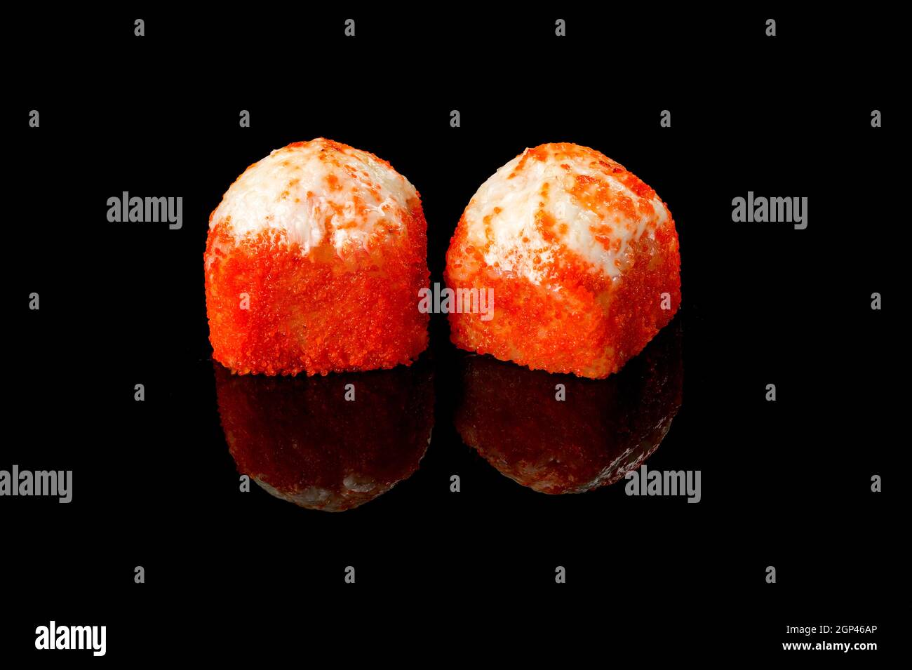 Two red tuna rolls with red caviar and shrimp on a black background ...