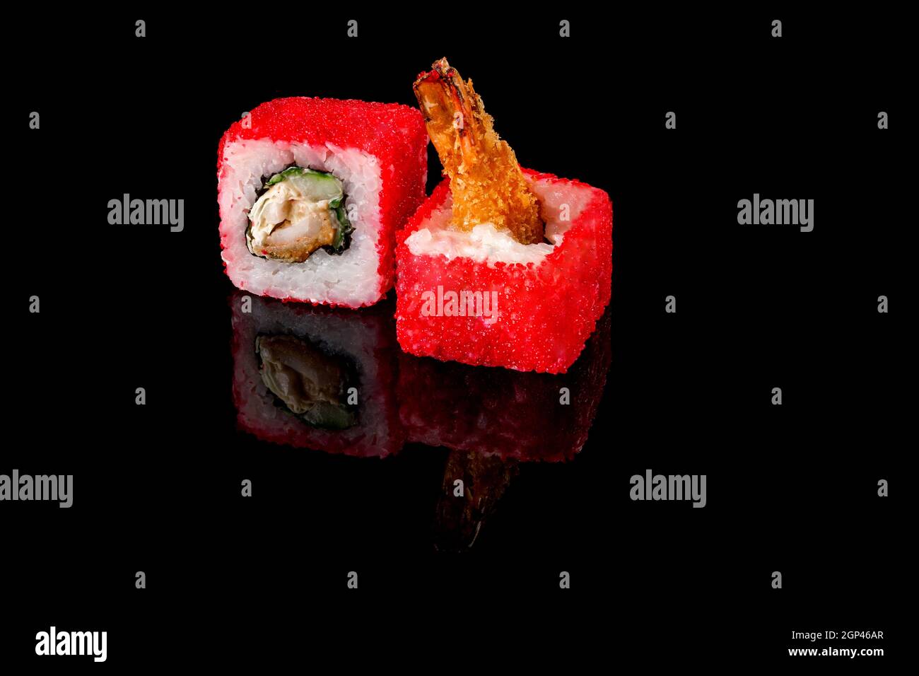 Two red tuna rolls with red caviar and shrimp on a black background ...