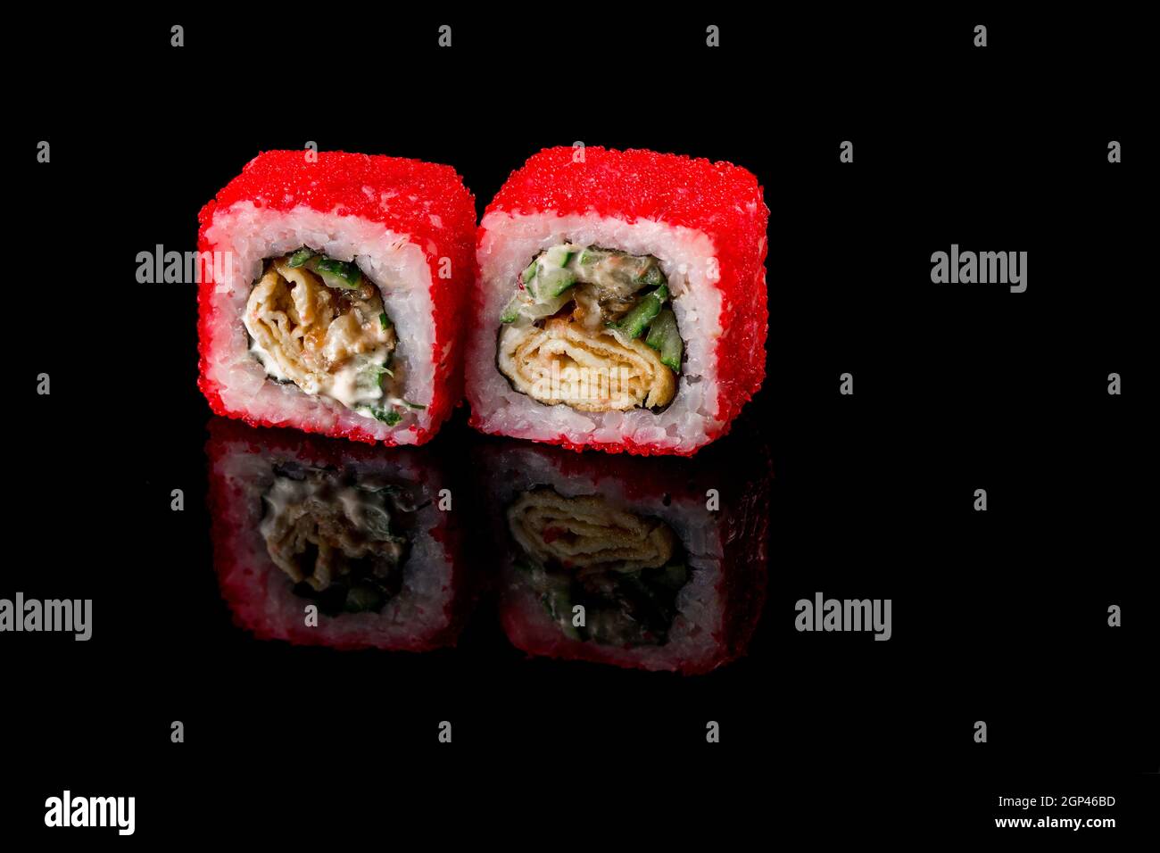 Two red tuna rolls with red caviar and shrimp on a black background ...