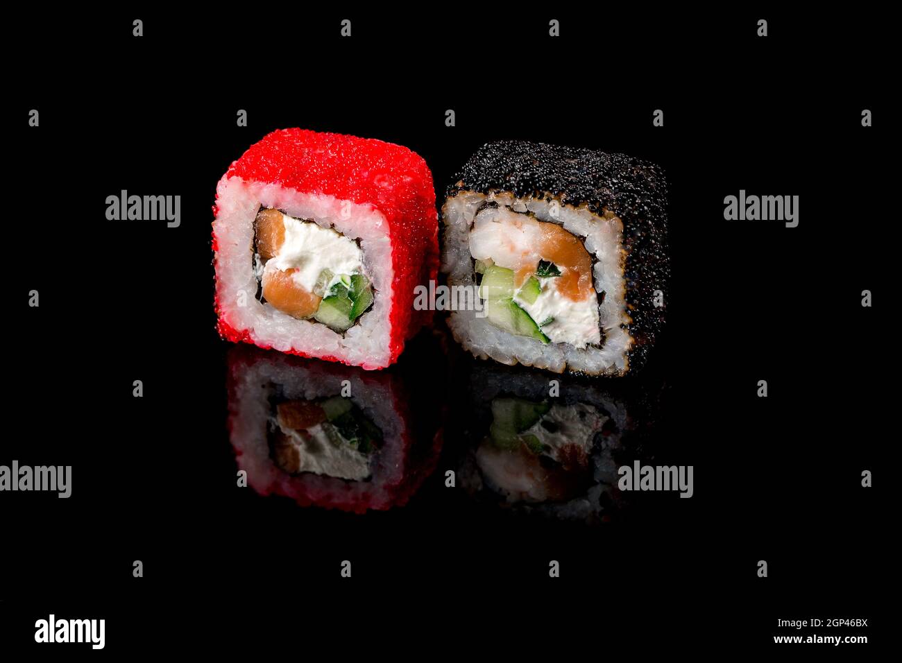 Two red tuna rolls with red caviar and shrimp on a black background ...