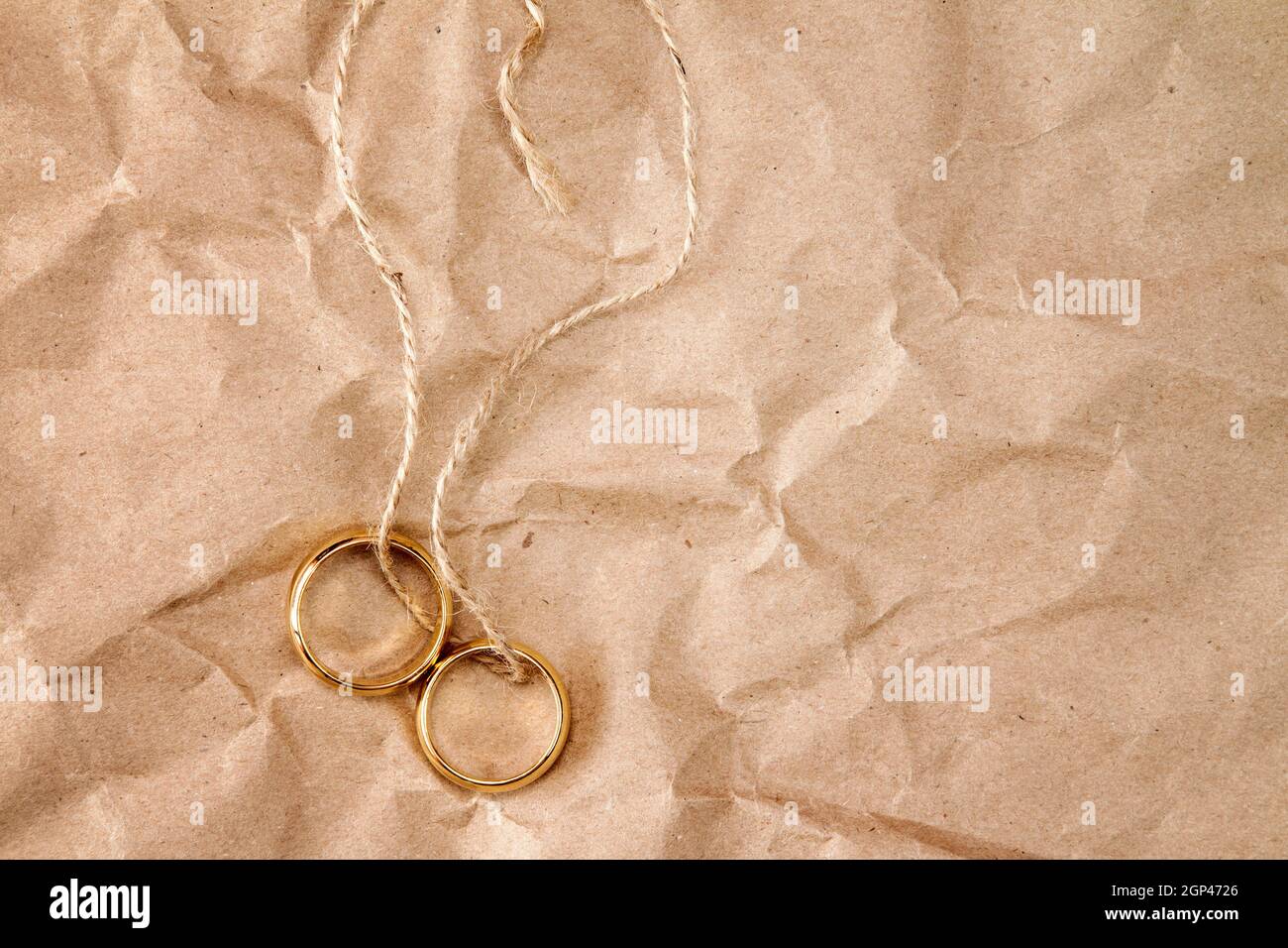 Two gold wedding rings tied with string over paper background Stock ...
