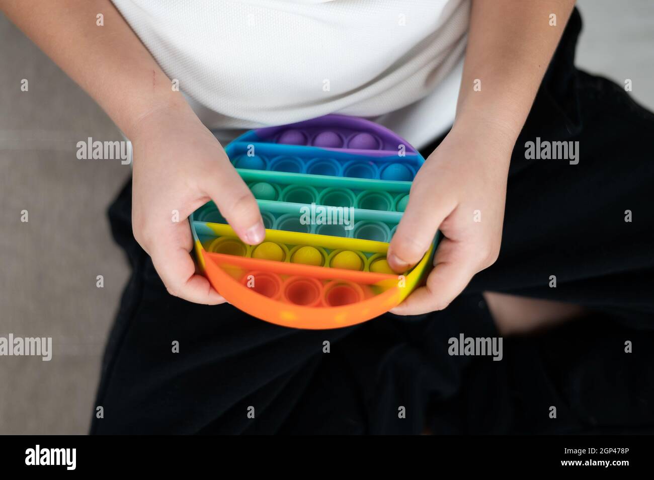 Faceless little boy playing pop it rainbow colors Stock Photo - Alamy