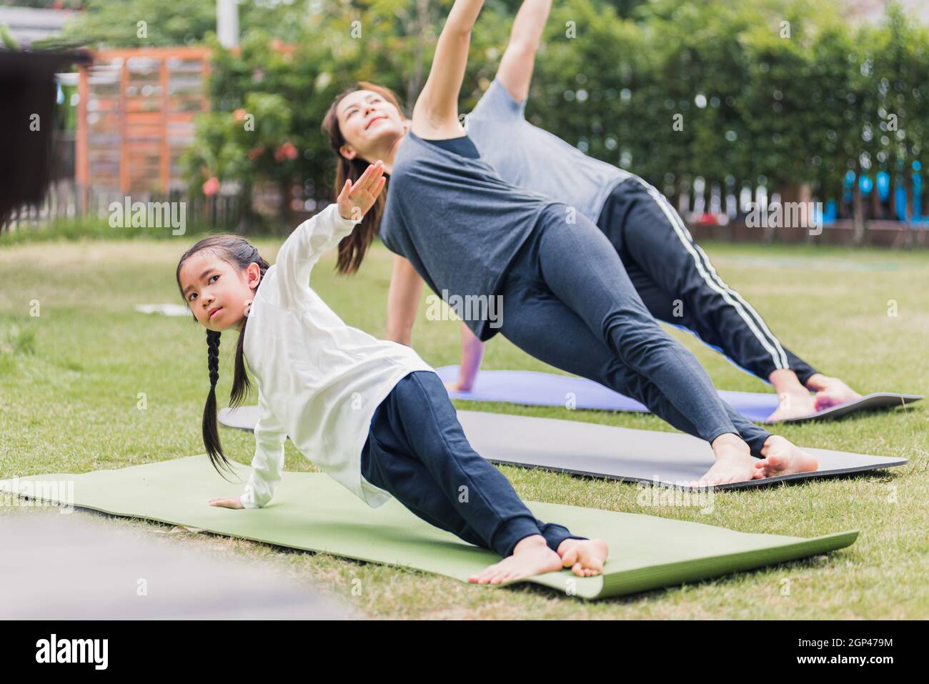 Asian young mother, father practicing doing yoga exercises with child ...