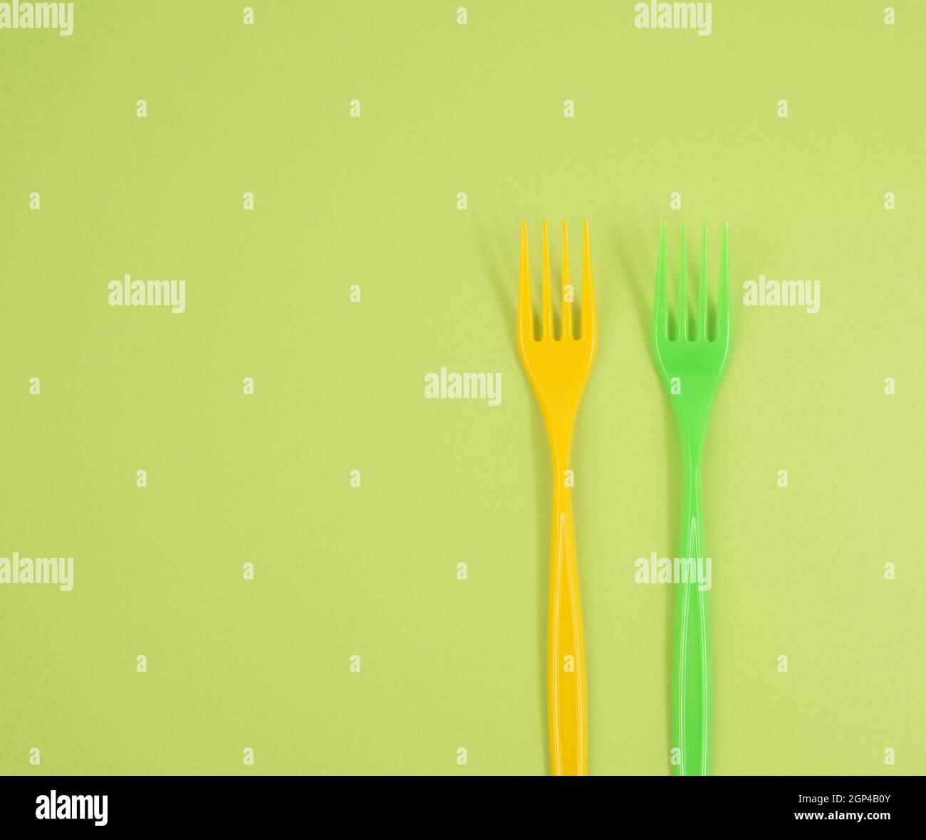 stack of plastic forks on a green background, top view, copy space ...