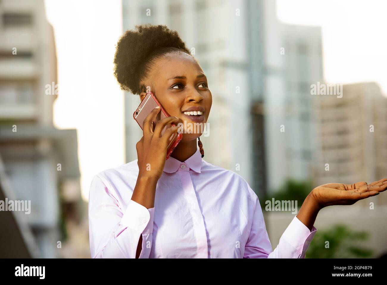 beautiful young woman standing aside and talking on the phone outdoors ...