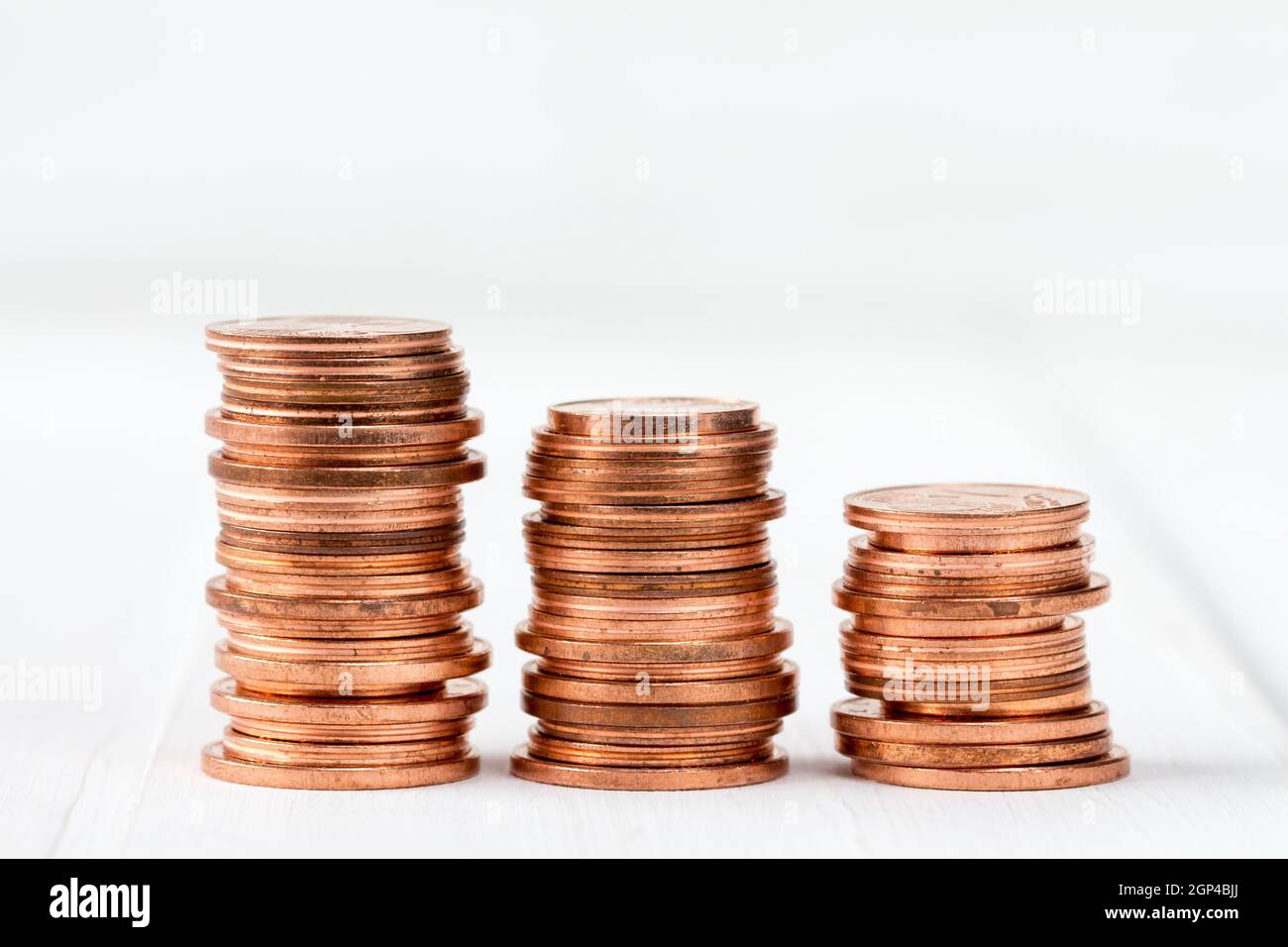 Three stacks of copper coins on white wooden background Stock Photo - Alamy