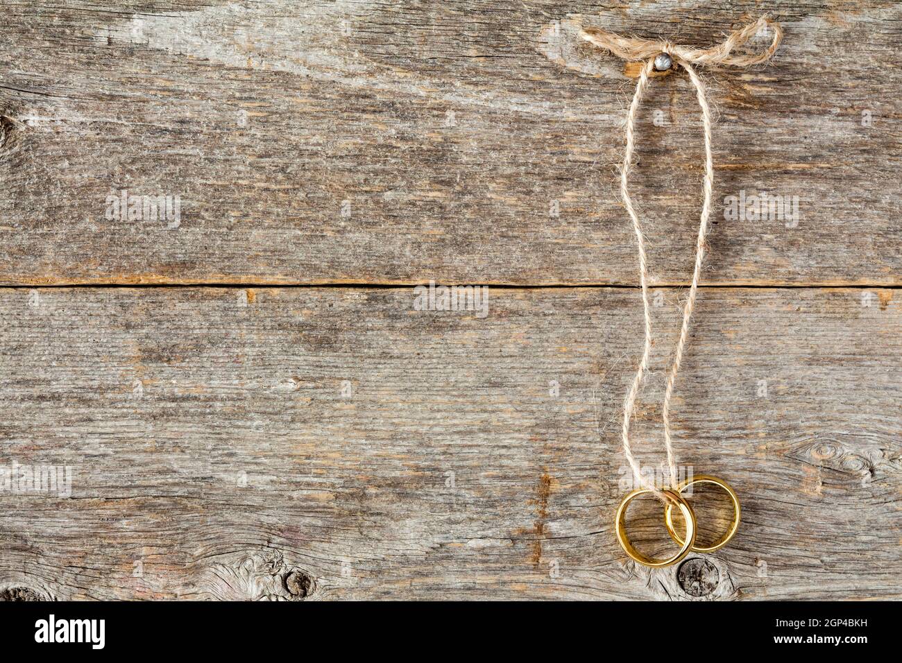 Two gold wedding rings tied with string hanging on wooden wall Stock ...