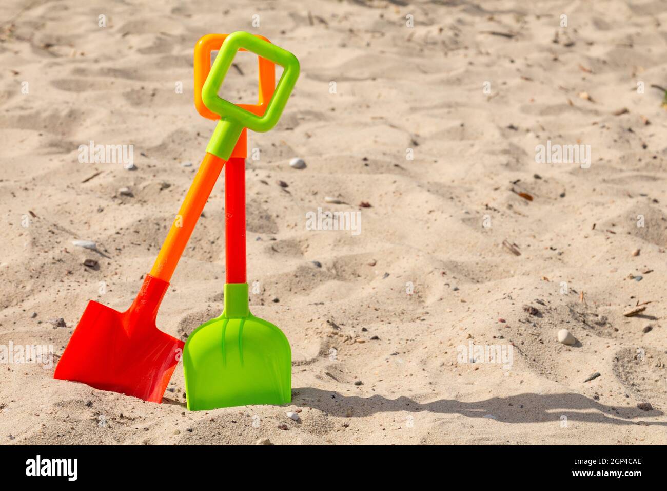 Two colorful plastic shovels on the beach sand Stock Photo - Alamy