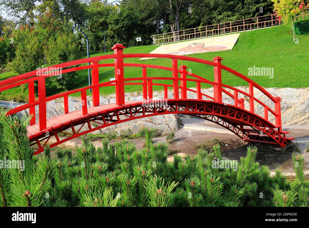 Old red wooden bridge across a small river in a green park. Vintage ...