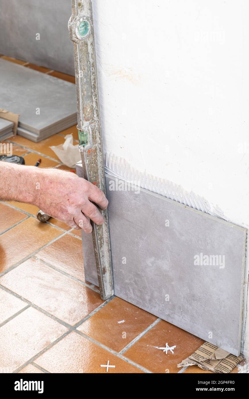 the tiler lays a ceramic tile on the wall Stock Photo - Alamy