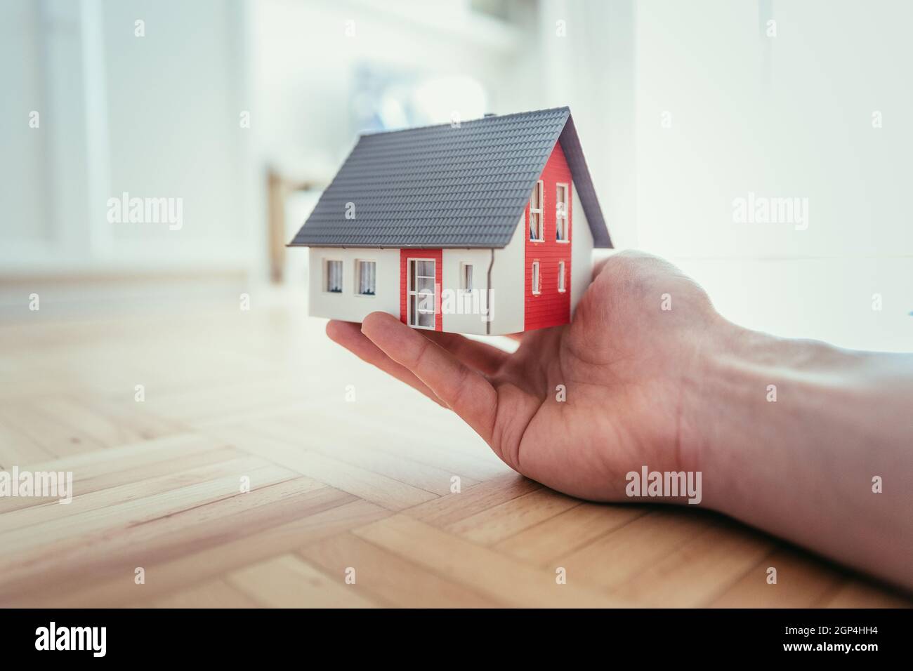 Adult hand is holding red house model, indoors. Concept for new home ...