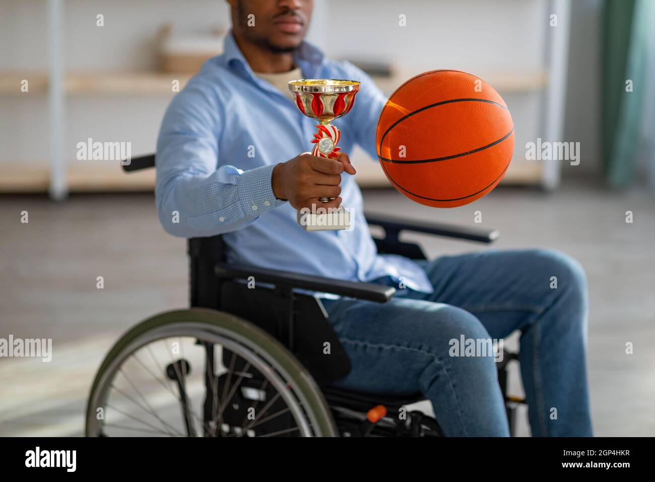 Unrecognizable black basketball player with ball and trophy sitting in ...