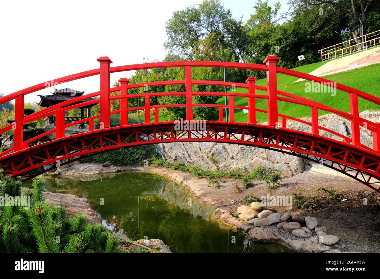 Old red wooden bridge across a small river in a green park. Vintage ...
