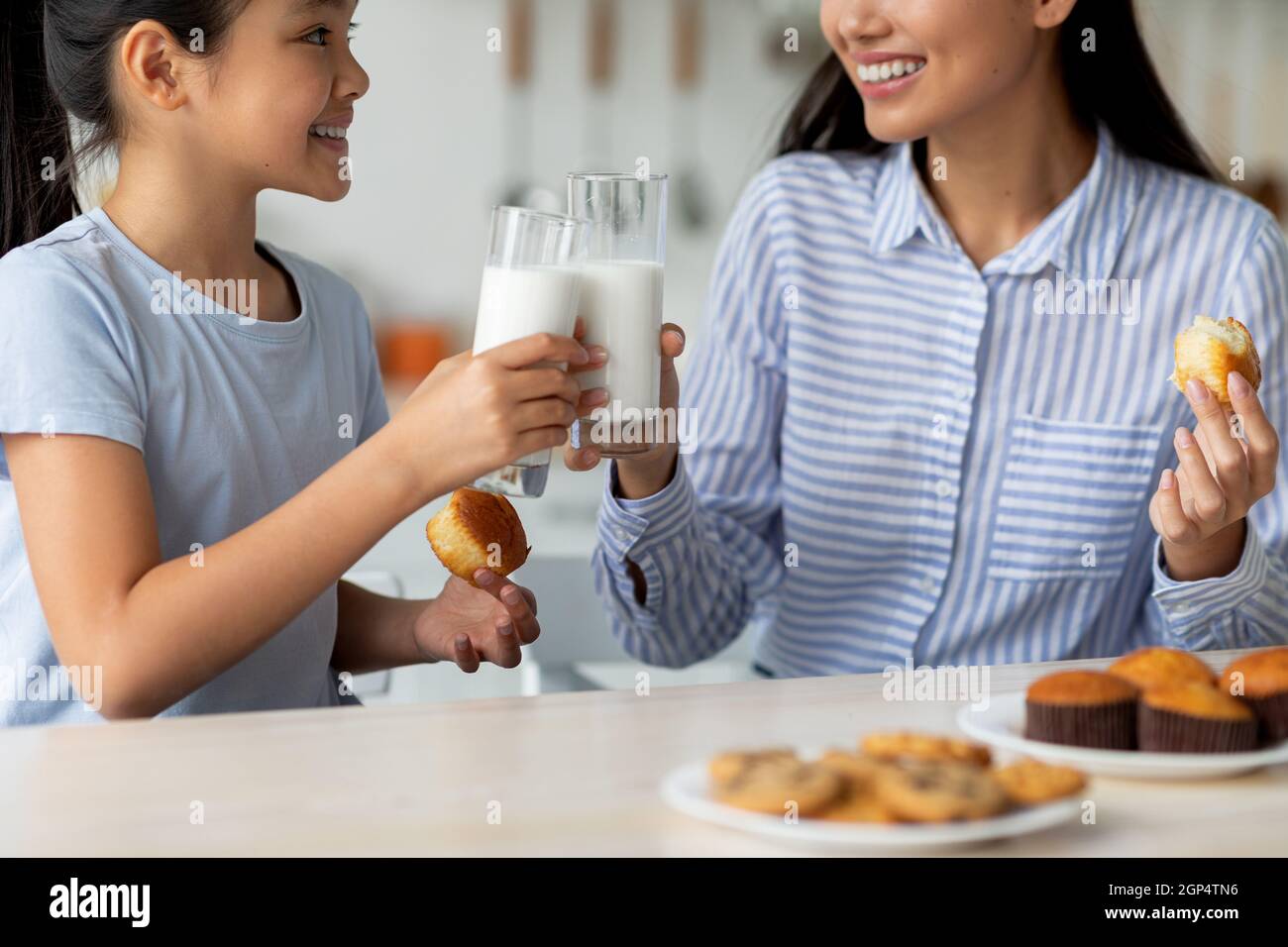 Time for vitamins. Asian girl and her young mother drinking milk in ...