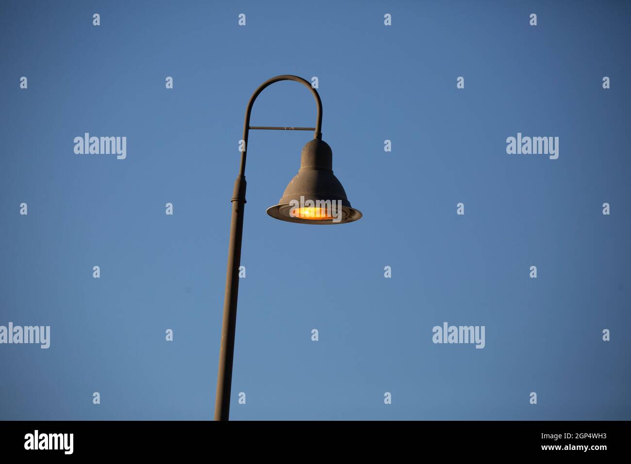 Overhead lamp with a glowing bulb during a bright blue day Stock Photo ...